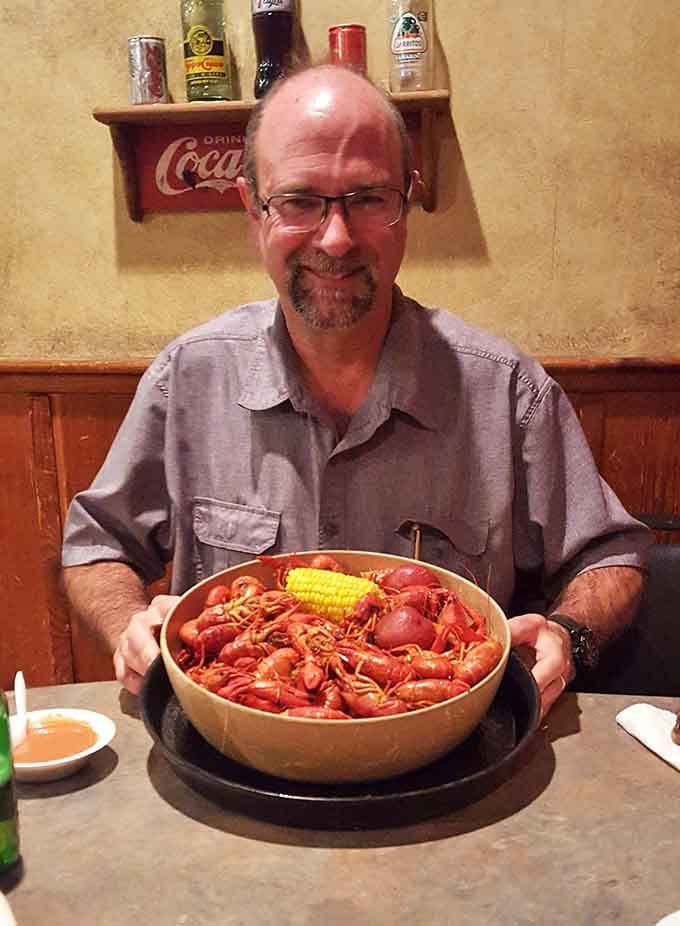A satisfied diner showcases a bowl of crawfish so perfect it could be the official poster child for Louisiana cuisine.
