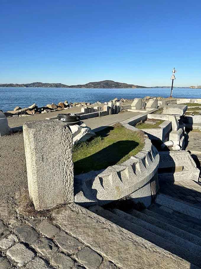 Sculptural elements frame the blue water beyond, where sailboats drift past this artistic tribute to sound and sea.