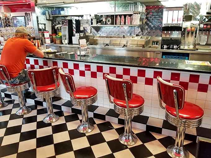 Classic diner counter seating with red stools lets you watch the kitchen magic happen in real time.