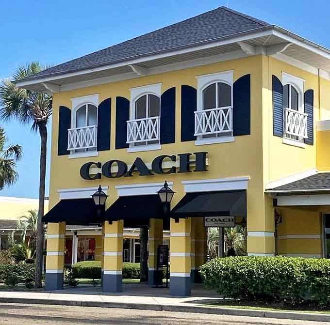 Coach stands like a leather-bound temple to accessory excellence. Those signature black awnings are actually capes, worn by your wallet's superhero&mdash;outlet pricing.