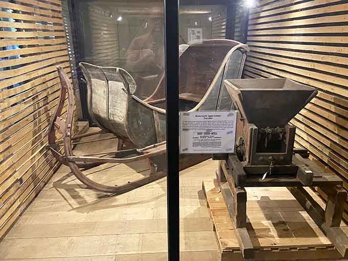 Antique farm equipment behind glass reminds us that apple cider once required serious muscle and determination.