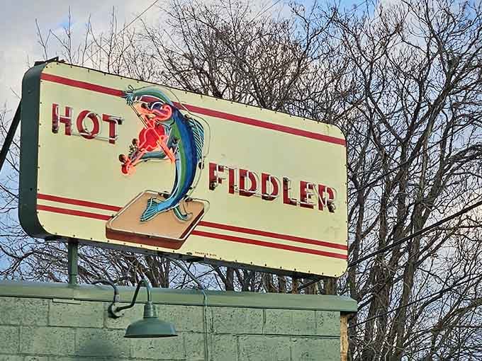 The Hot Fiddler sign standing proud against winter trees, a beacon for hungry travelers who know good food when they see it.