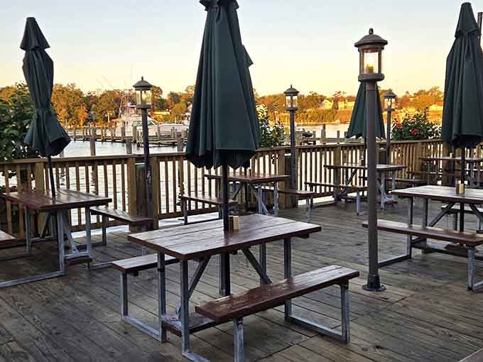 The waterfront deck at sunset, where picnic tables and umbrellas await diners who understand that seafood tastes better with a view.