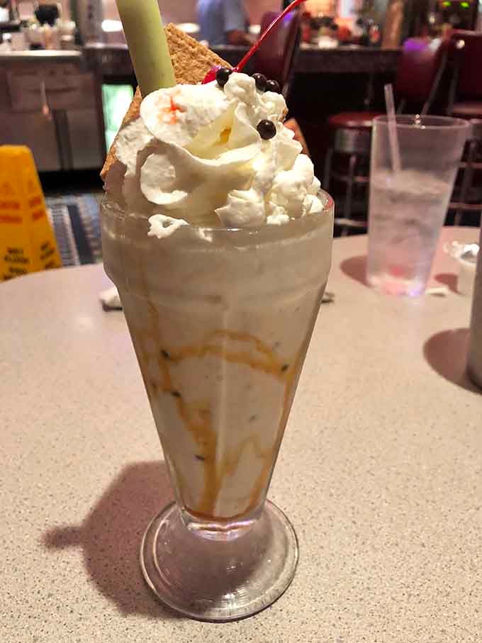 That milkshake stands tall with whipped cream, a cherry, and enough sweetness to justify skipping your afternoon coffee completely.