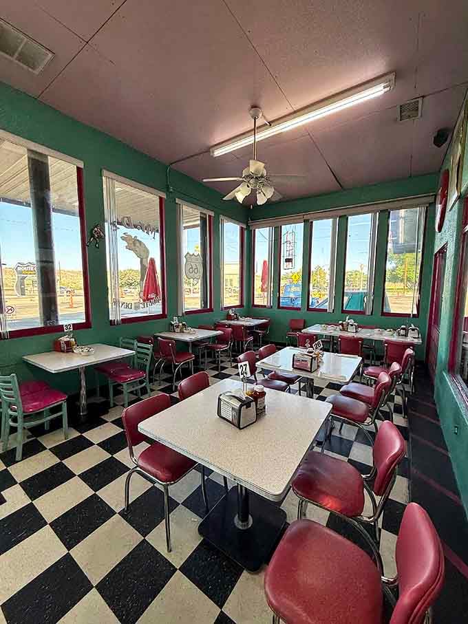 Window-lined dining room with checkered floors where every table offers views of Route 66 rolling past outside.