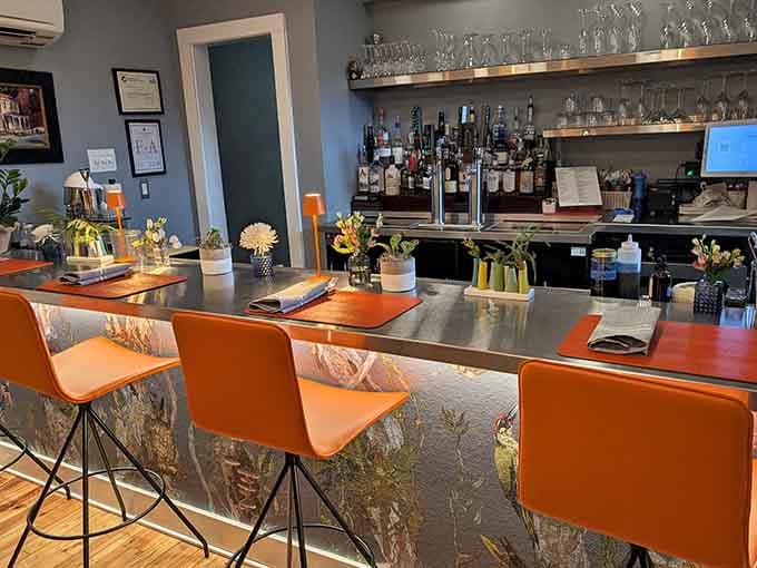 The sleek bar area features bright orange seating and a well-stocked selection for those who appreciate good drinks.