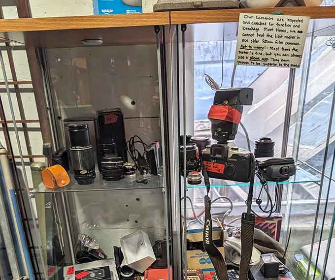 Camera equipment behind glass like a museum of memories, lenses and flashes ready to capture life's next great moments.