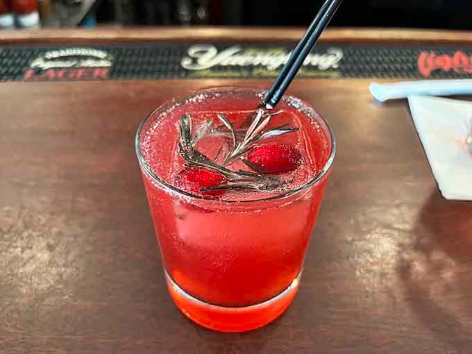 A vibrant cocktail garnished with fresh rosemary proves the bar program matches the kitchen's commitment to quality and presentation.