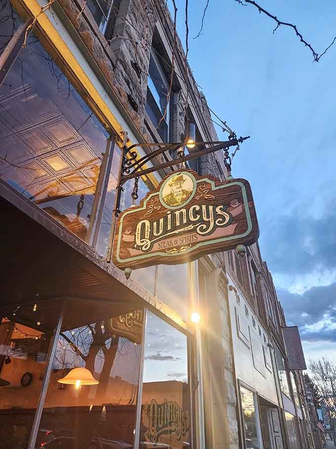 The vintage-style sign hanging at dusk looks like something from a classic Western, inviting you inside for adventure.