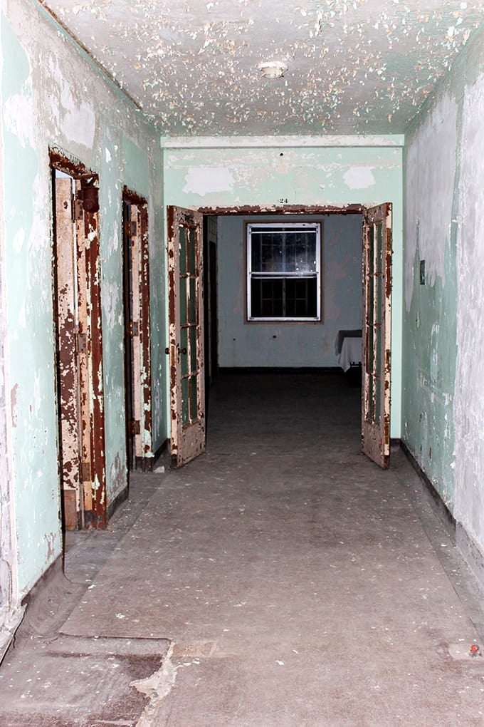 Mint-green paint peels from walls that have absorbed decades of human emotion, creating an atmosphere you can practically feel.