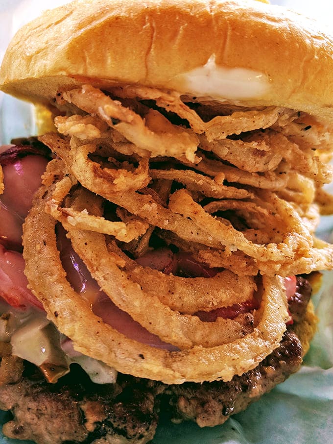 A burger topped with a small village of crispy onion rings. It's not excess if it's necessary.