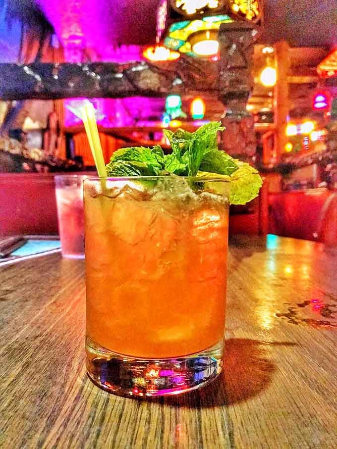 A Mai Tai garnished with fresh mint, glowing under tiki lights like liquid vacation in a glass.