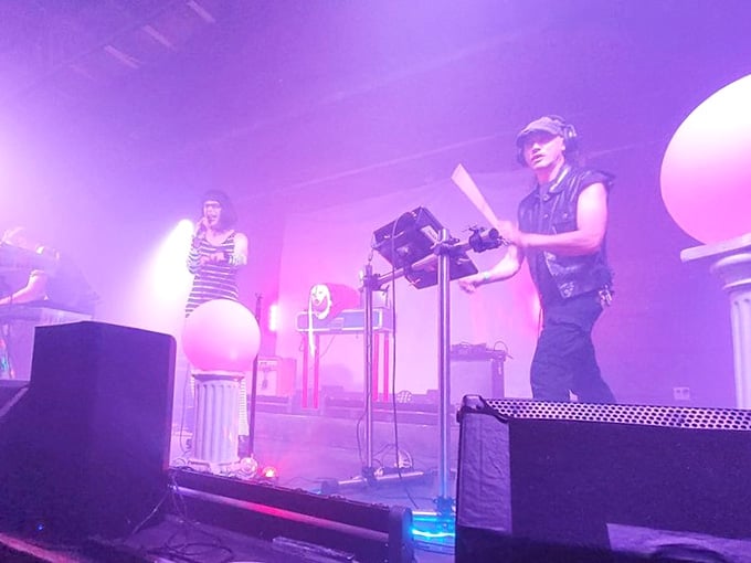 Live performances under purple lights create an atmosphere where music and macabre aesthetics blend into something genuinely special.