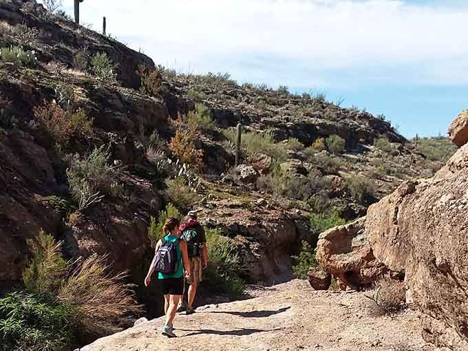 Hikers disappear into rocky terrain where adventure awaits around every sun-baked corner, no reservations or tickets required here.