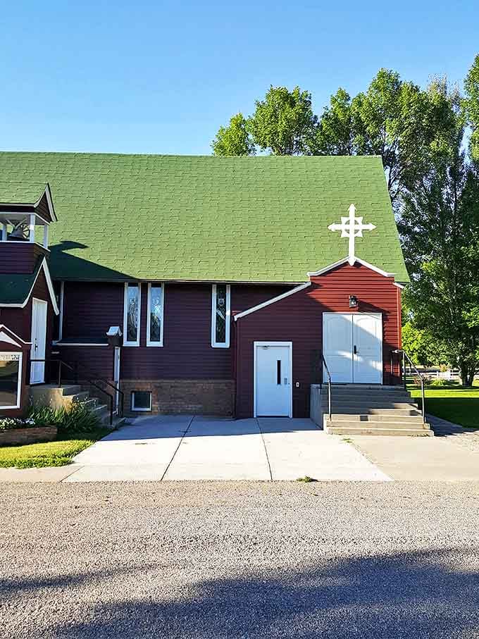 A modest church stands ready to serve, its green roof a beacon in this tight-knit community.