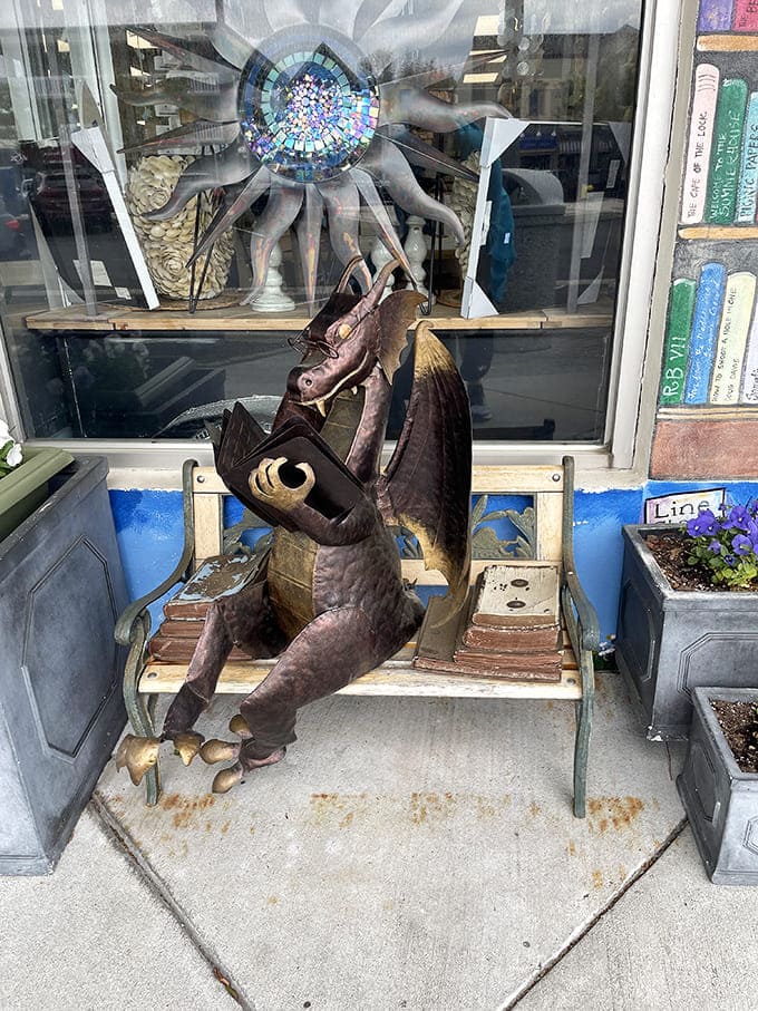 A metal dragon guards literary treasures while demonstrating proper bench etiquette&mdash;tail tucked, book in hand, ready for adventure.