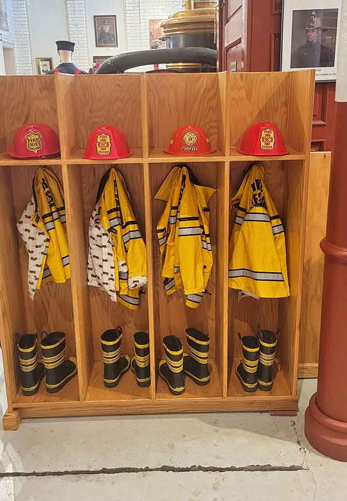 Firefighter gear stands at attention, yellow coats and red helmets waiting for the next generation to try them on.