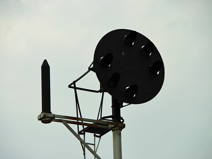 The railway signal stands silhouetted against gray skies, once guiding engineers through darkness and uncertainty with precision.