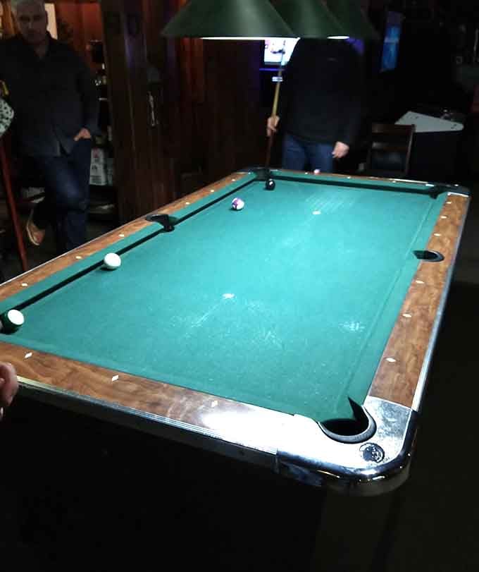 The pool table under moody lighting where friendly competition and trash talk have flourished for generations.