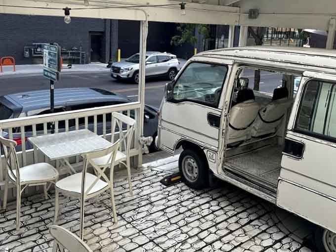 The patio seating extends the illustrated theme outside, complete with a van that may or may not be real.