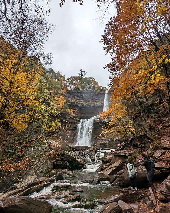 Autumn paints the perfect backdrop as hikers pause to absorb the view from the rocky streambed.