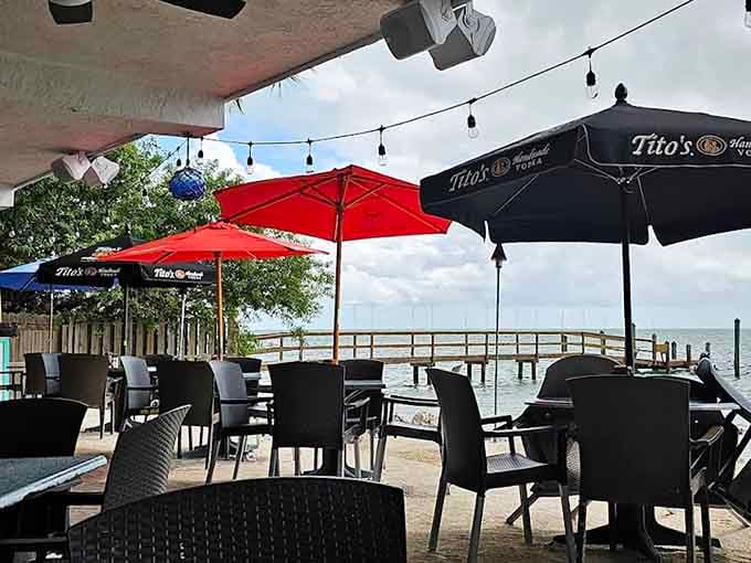 Red umbrellas shading outdoor tables by the pier, creating postcard-perfect spots for sunset dining and vacation memories.