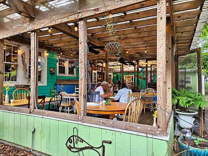 Rustic wooden pergola overhead and mismatched chairs below, creating an atmosphere that's effortlessly charming and completely inviting.
