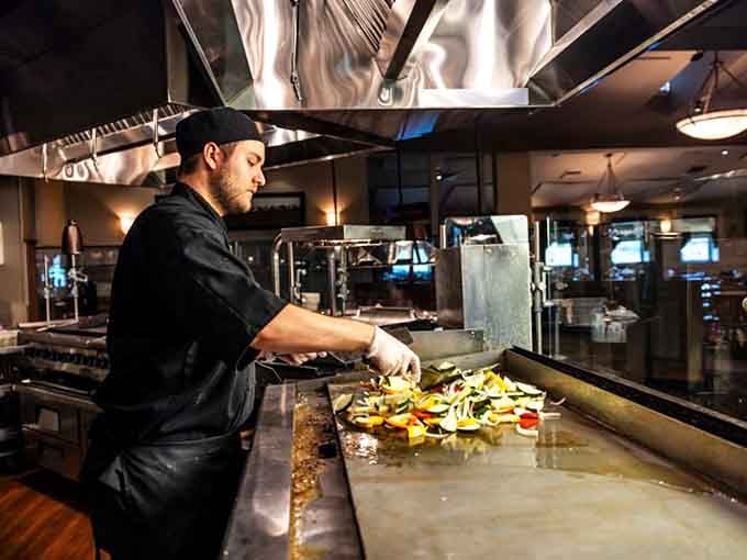 A chef works the grill with practiced precision, ensuring every dish meets the restaurant's exacting standards.