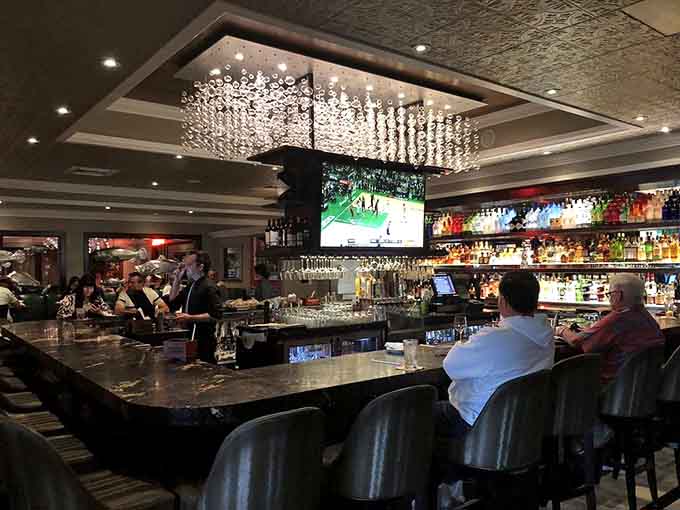 The bar area glows with elegant chandeliers, creating an upscale atmosphere perfect for pre-dinner drinks or post-work unwinding.