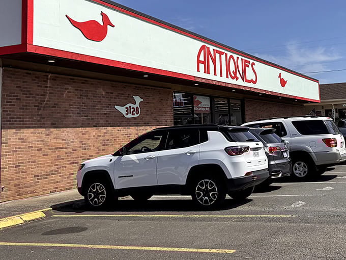 The red-and-white facade stands like a beacon for bargain hunters. Those parked cars contain empty trunks just waiting to be filled with history.