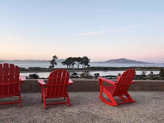 Red chairs facing the bay at sunset, because sometimes the best seat in the house is literally just a chair.