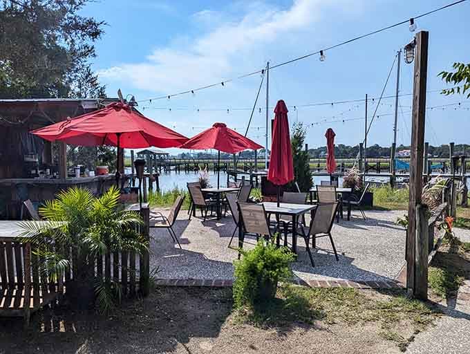 Outdoor seating with red umbrellas overlooking Shem Creek—where shrimp boats and sunset views come standard with dinner.