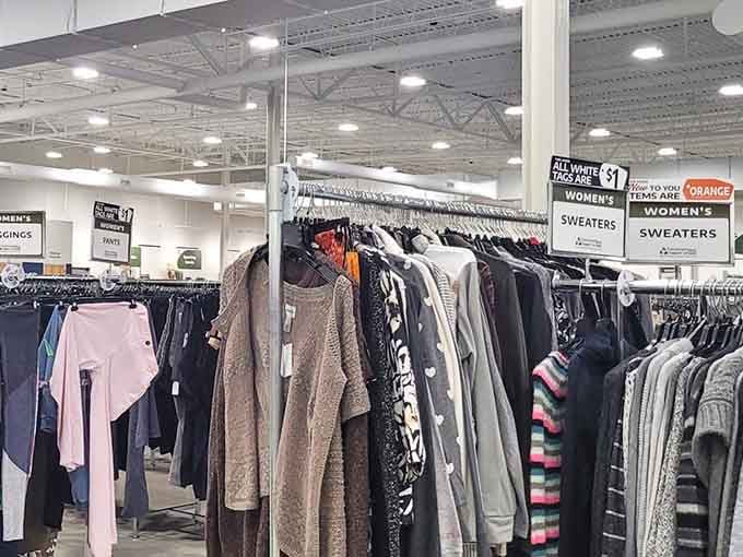 Rows of sweaters stretch endlessly under bright warehouse lights, promising hidden treasures at every turn.