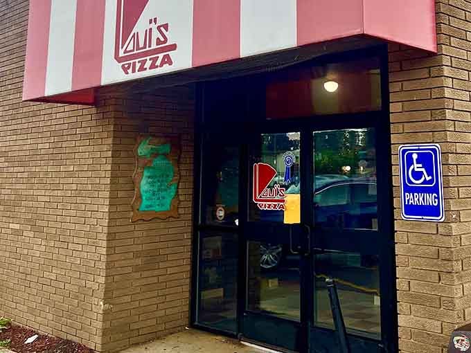 The iconic pink and white striped awning of Loui's Pizza beckons hungry travelers like a delicious mirage in Hazel Park.