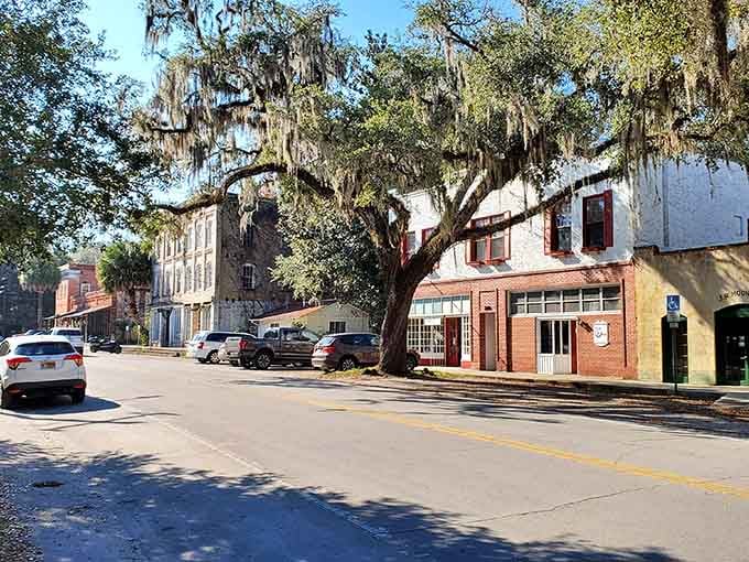 Spanish moss drapes like nature's lace curtains over this timeless street where history whispers from every weathered storefront.