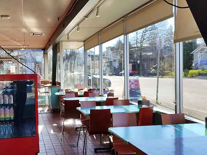 Bright turquoise tables and floor-to-ceiling windows create a cheerful space that feels both retro and fresh.