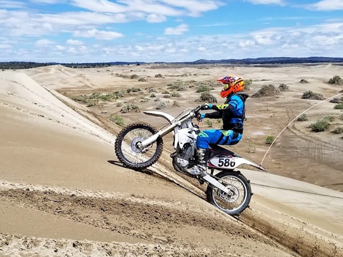 Dirt bike riders tackle steep dune faces where the high desert meets adventure and adrenaline.
