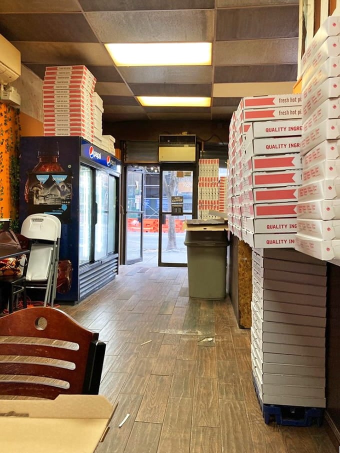 Stacks of pizza boxes tower like delicious skyscrapers, promising carb-loaded happiness to patient souls who wait.