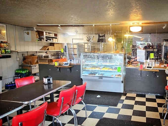 Classic diner vibes meet donut paradise: checkered floors, red chairs, and a display case full of golden possibilities.
