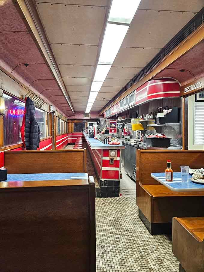 The narrow aisle between counter and booths is where servers perform their daily choreography with remarkable grace.