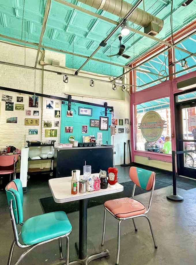 Retro turquoise chairs and pink accents create a 1950s time capsule where the only thing missing is a jukebox.