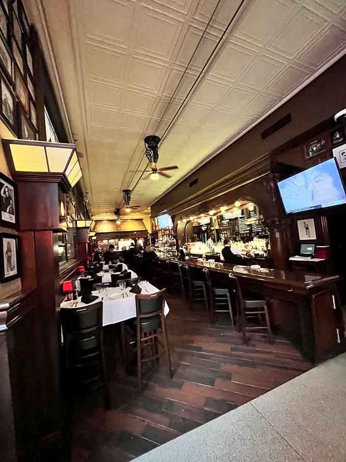 Dark wood, white tablecloths, and tin ceilings create the kind of timeless atmosphere that makes every meal feel important.