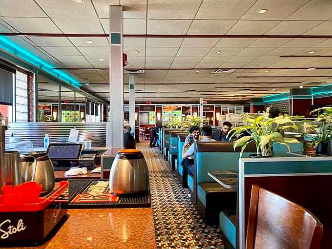 Classic blue booths and neon lighting create that perfect diner atmosphere where important life decisions—like pancakes versus waffles—are contemplated daily.