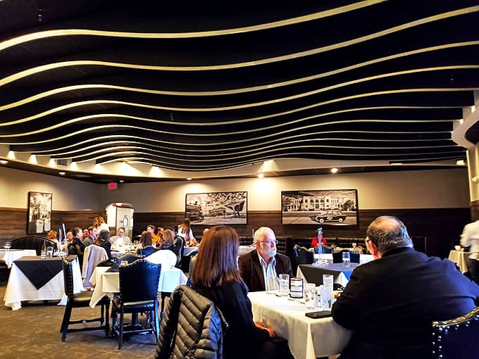 The elegant wave-patterned ceiling guides your eyes across the dining room, where Kansas beef dreams come true beneath golden accents and warm lighting.