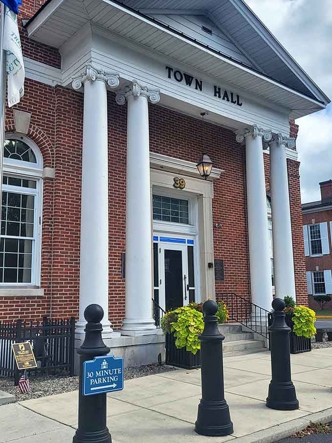 The Town Hall's elegant entrance welcomes visitors with classical columns and vibrant planters – small-town governance with unexpected architectural flair.