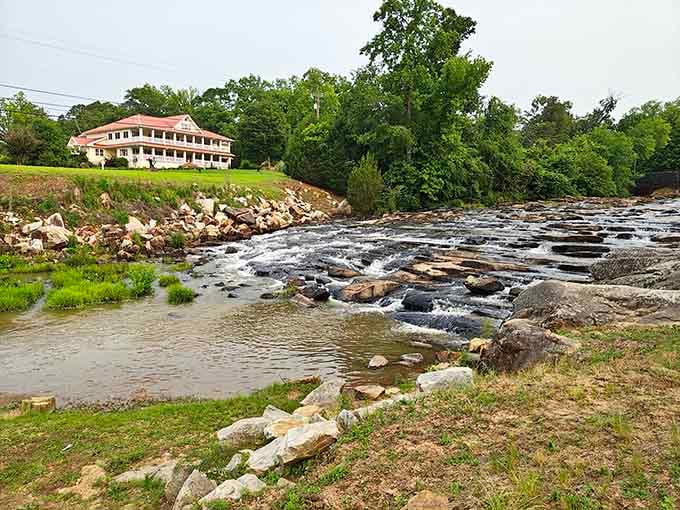 Water cascades over ancient rocks while that historic building watches from the hillside like a patient guardian.