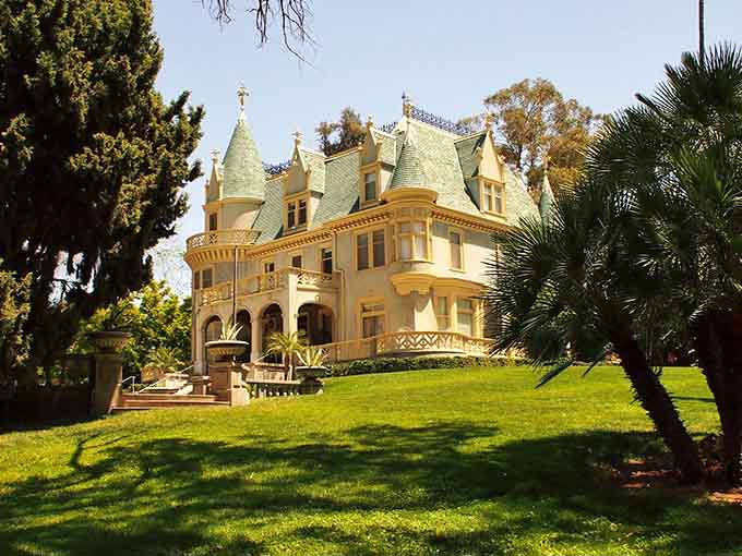 Golden afternoon light bathes the cream-colored facade, turning this hilltop mansion into pure California elegance with European flair.