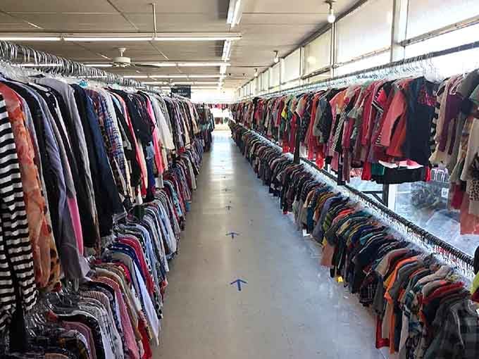 These clothing racks stretch toward infinity like a fabric rainbow, organized perfectly for serious treasure hunters with shopping carts.