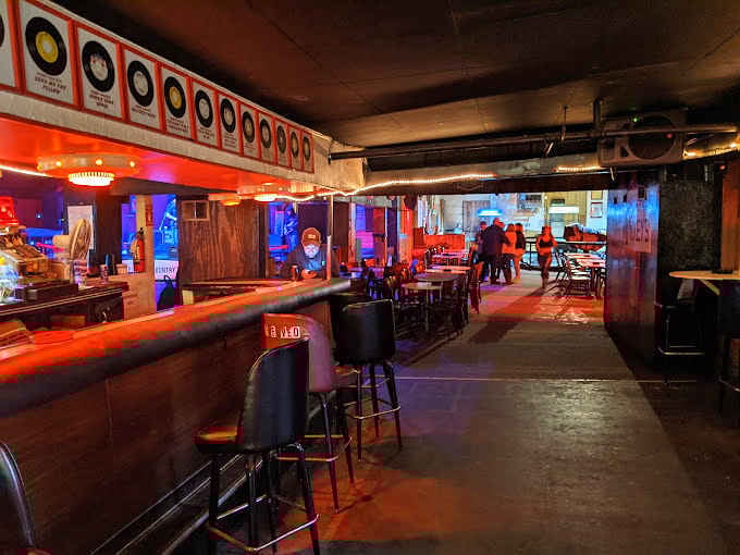 The interior bathes in red light, creating an atmosphere that's equal parts honky-tonk and horror film set.