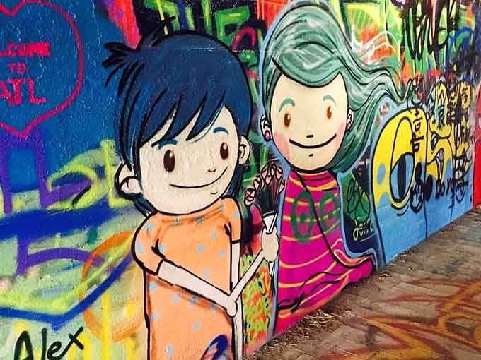 Two cheerful characters hold hands on this wall, proving that even cartoon figures appreciate good street art companionship.